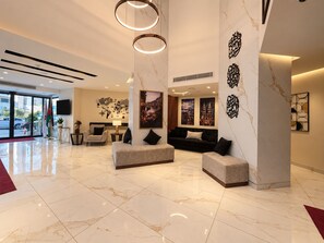 Um hall amplo com piso de mármore, dois sofás, uma mesa de centro e um mapa-múndi na parede.
