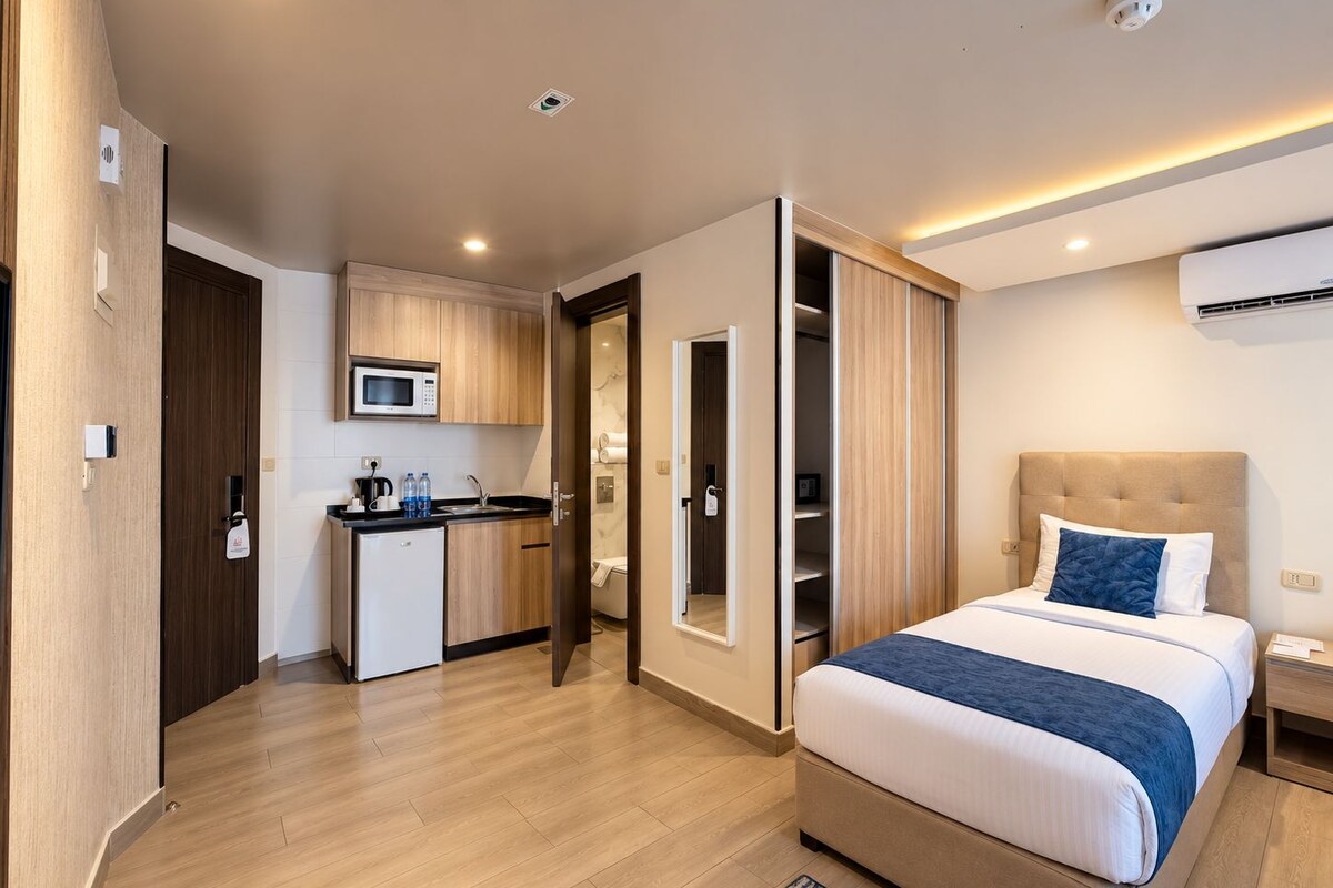 Quarto de hotel moderno com cama, pequeno espaço de cozinha e closet amplo.