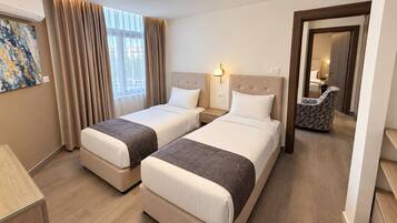 Quarto de hotel com duas camas, um espaço para sentar e vista para o exterior.