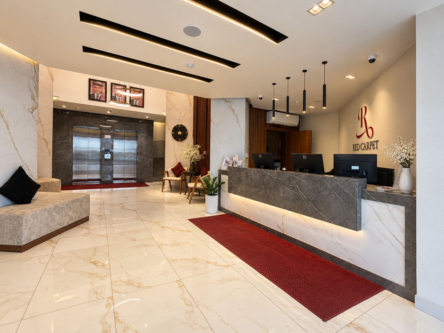 Uma área de recepção de hotel com piso de mármore, balcão de atendimento, um relógio e uma câmera de segurança.