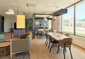 Um espaço de escritório moderno com uma mesa grande, cadeiras e vista para o exterior.