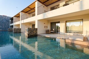 Um edifício moderno de dois andares com piscina, paredes de pedra e uma varanda.