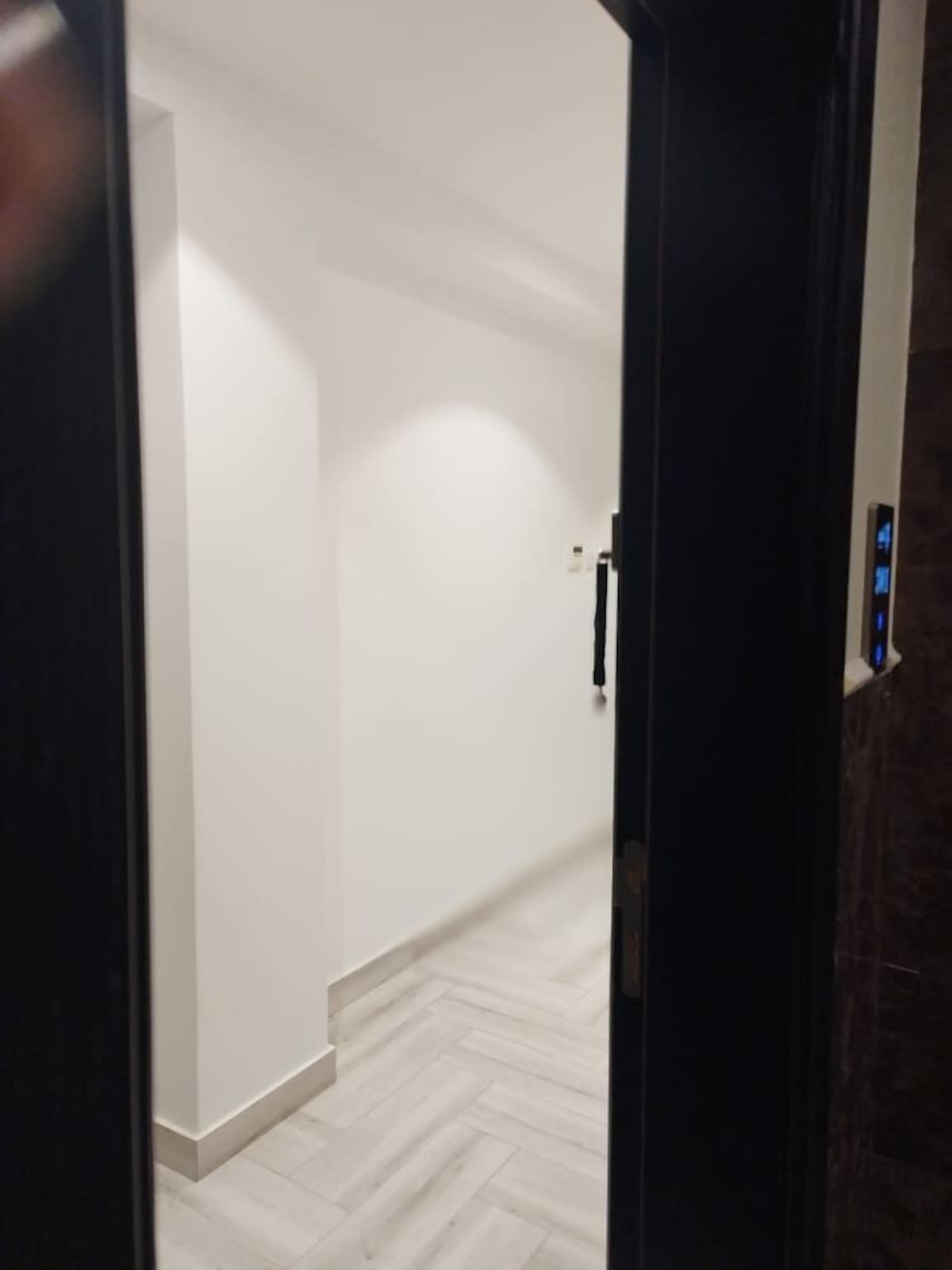 Corredor com piso claro e porta com fechadura digital.