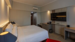 Quarto de hotel moderno com uma cama grande, abajures, uma escrivaninha, televisão de tela plana e ar condicionado.