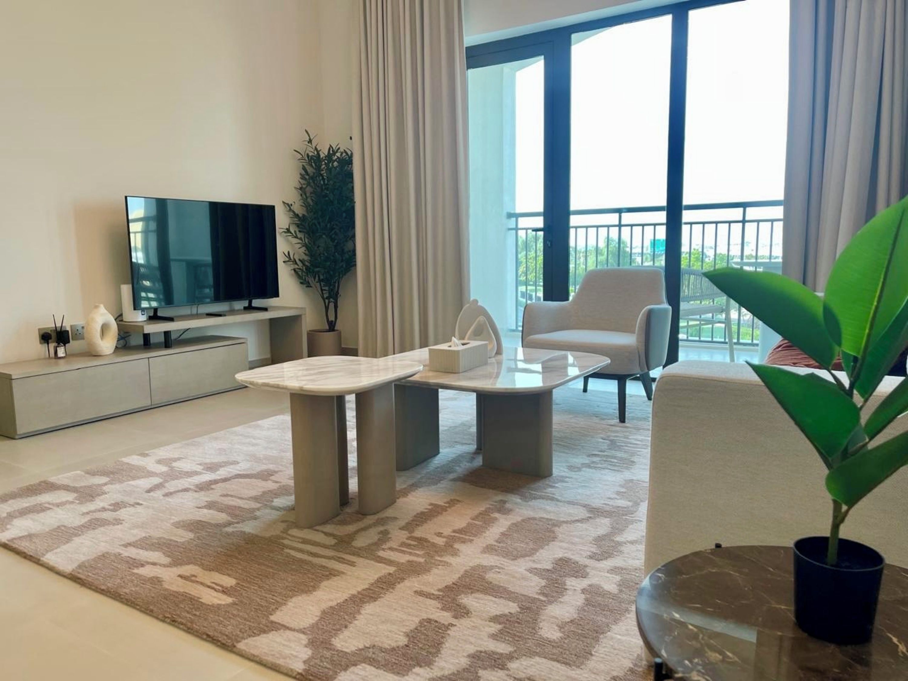 Uma sala de estar moderna com televisão de tela plana, mesa de centro, sofá e planta em vaso.