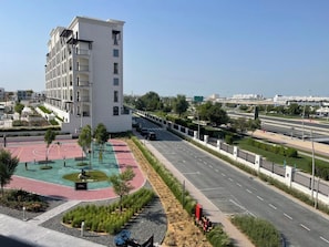 Um edifício de vários andares com quadra de basquete e uma estrada com cerca.