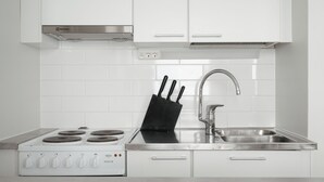 Uma cozinha moderna com armários brancos, fogão de aço inoxidável, pia e porta-facas.