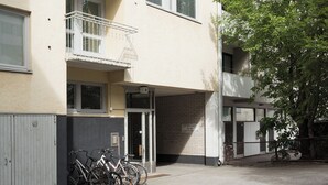 Um edifício residencial com vários andares, varandas, portão fechado e bicicletas estacionadas na frente.