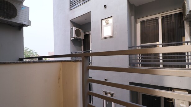 Um edifício de vários andares com varandas, aparelhos de ar condicionado e janelas.