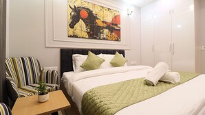 Quarto de hotel com cama, cadeira, mesa e um quadro na parede.