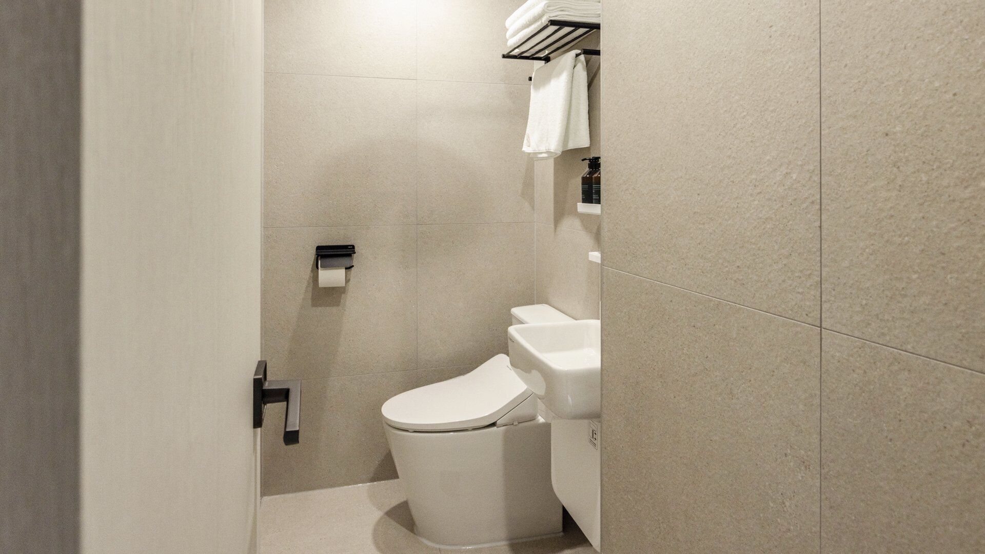 Um banheiro moderno com vaso sanitário, porta-toalhas e dispensador de papel.