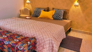 Uma cama com roupa de cama estampada, uma mesa de cabeceira e luminárias fixadas na parede.