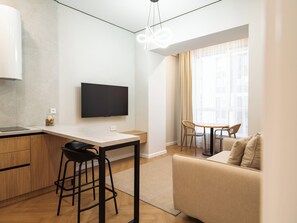 Uma cozinha moderna com televisão de tela plana, armários de madeira, um banco de bar e uma área de jantar com mesa e cadeiras.