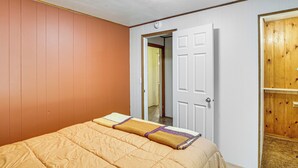 Quarto com cama, porta e parede de painéis de madeira.