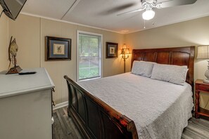 Quarto com cama, escrivaninha, ventoinha no teto e janela com persianas.