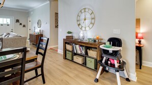 Uma área de refeições com mesa de madeira, cadeiras e uma cadeirinha para bebê.