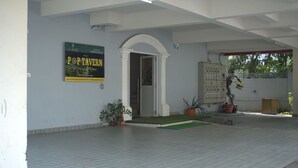 Uma área de recepção limpa e com azulejos, com uma placa indicando 'P Tavern' e um vaso de plantas.