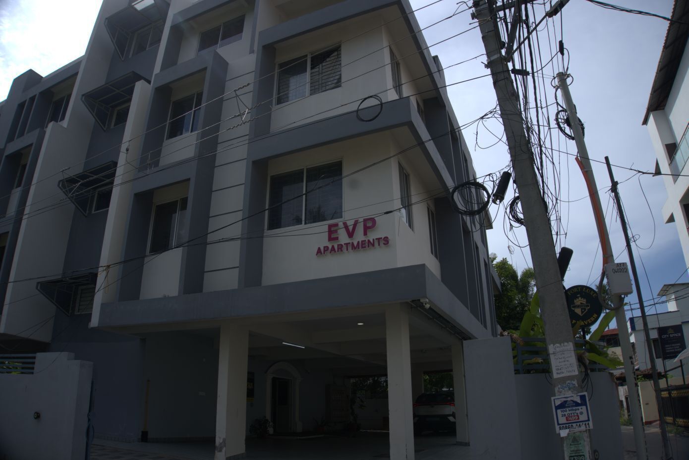 Um edifício de vários andares com a placa 'EVP APARTMENTS', indicando que se trata de um complexo de apartamentos.