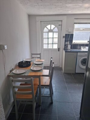 Uma cozinha compacta com área de refeições, máquina de lavar e janela com persianas.