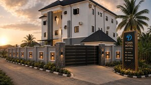 Hotel moderno com entrada gradeada, vários andares e placa indicando serviços de hospedagem, restaurante, conferências e eventos.