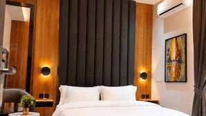Quarto moderno com cama grande, painel de parede de madeira e luminária no teto.