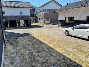 Um bairro residencial com casas, um caminho de acesso de cascalho e um carro estacionado.