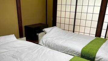 Quarto de hotel com duas camas, cabeceira de madeira e um painel shoji.