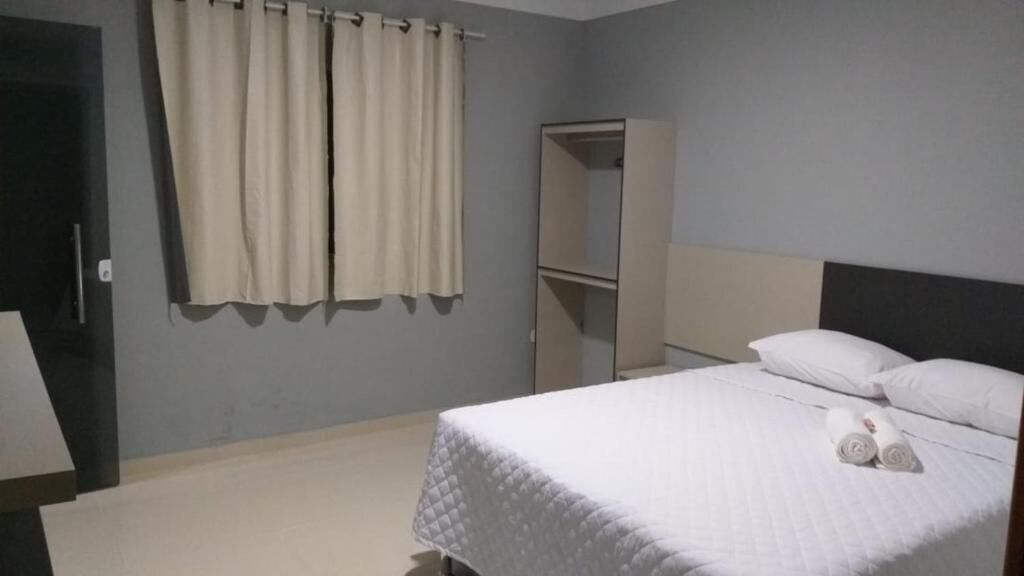 Quarto com cama, guarda-roupa e cortina.