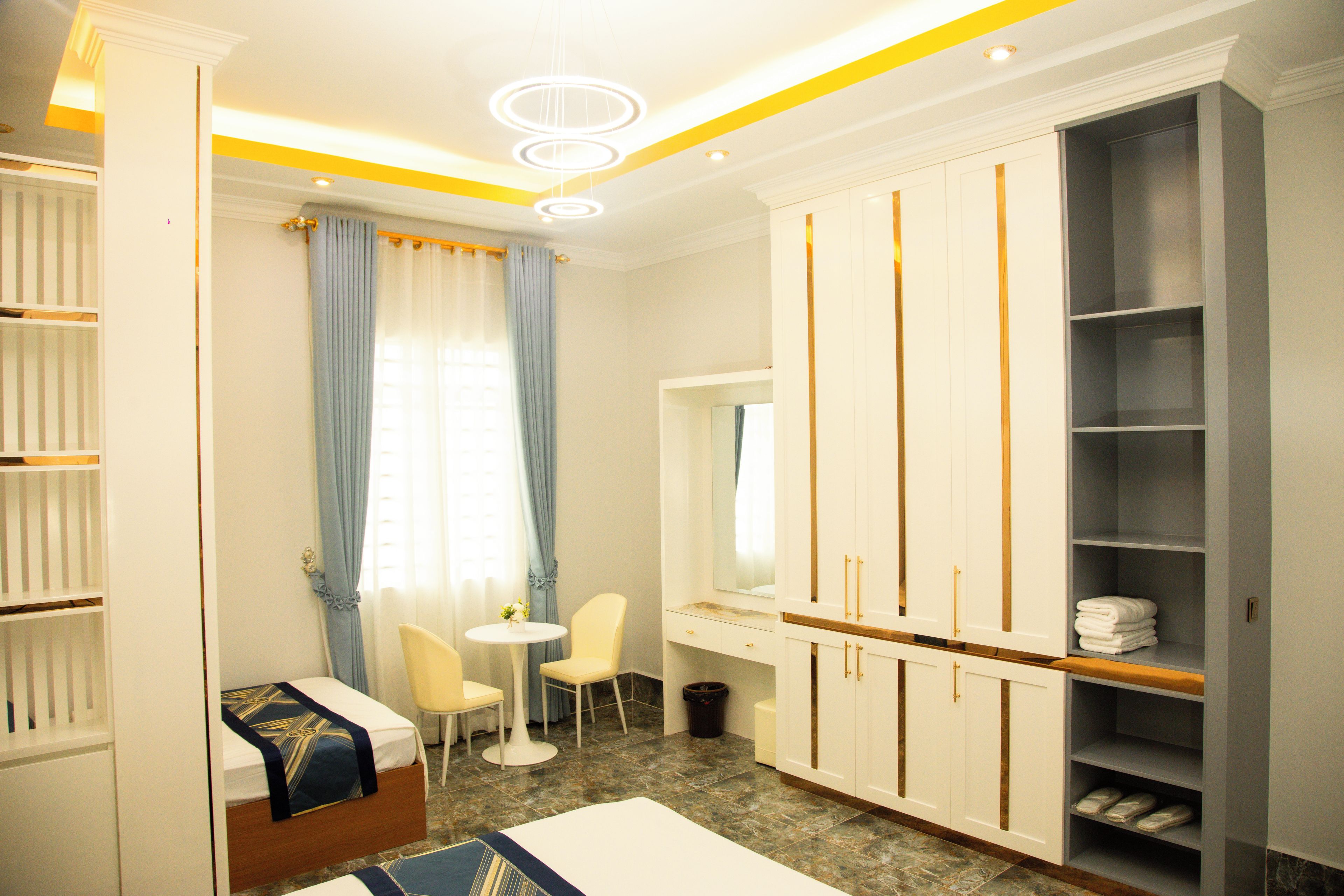 Quarto de hotel com cama, área de estar com cadeiras, pequena mesa, guarda-roupa e banheiro.