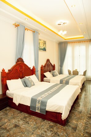 Quarto de hotel com duas camas de madeira, piso de mármore e um quadro na parede.