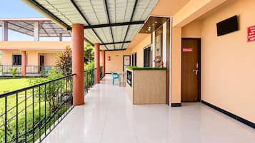 Corredor com balcão de recepção, placa indicando o salão de refeições e área externa verde com cerca.