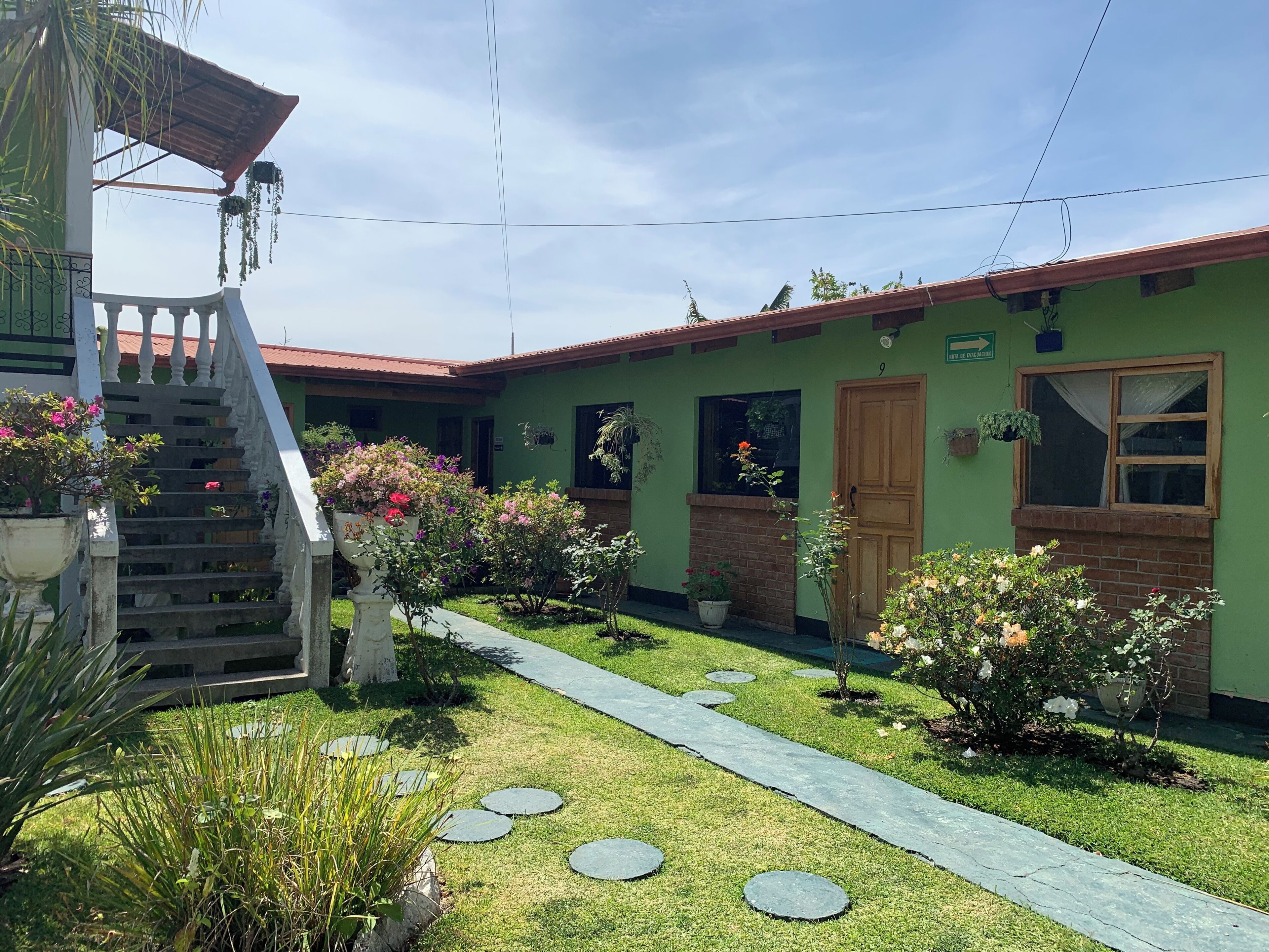 Um edifício verde com escadas, uma parede de tijolos e uma janela.