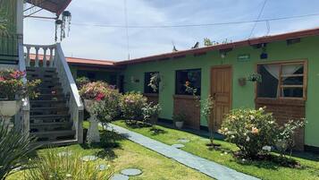 Um edifício verde com escadas, uma parede de tijolos e uma janela.