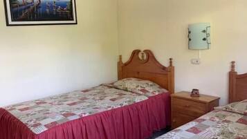 Quarto com duas camas, uma mesa de cabeceira, uma luminária na parede e um quadro emoldurado.