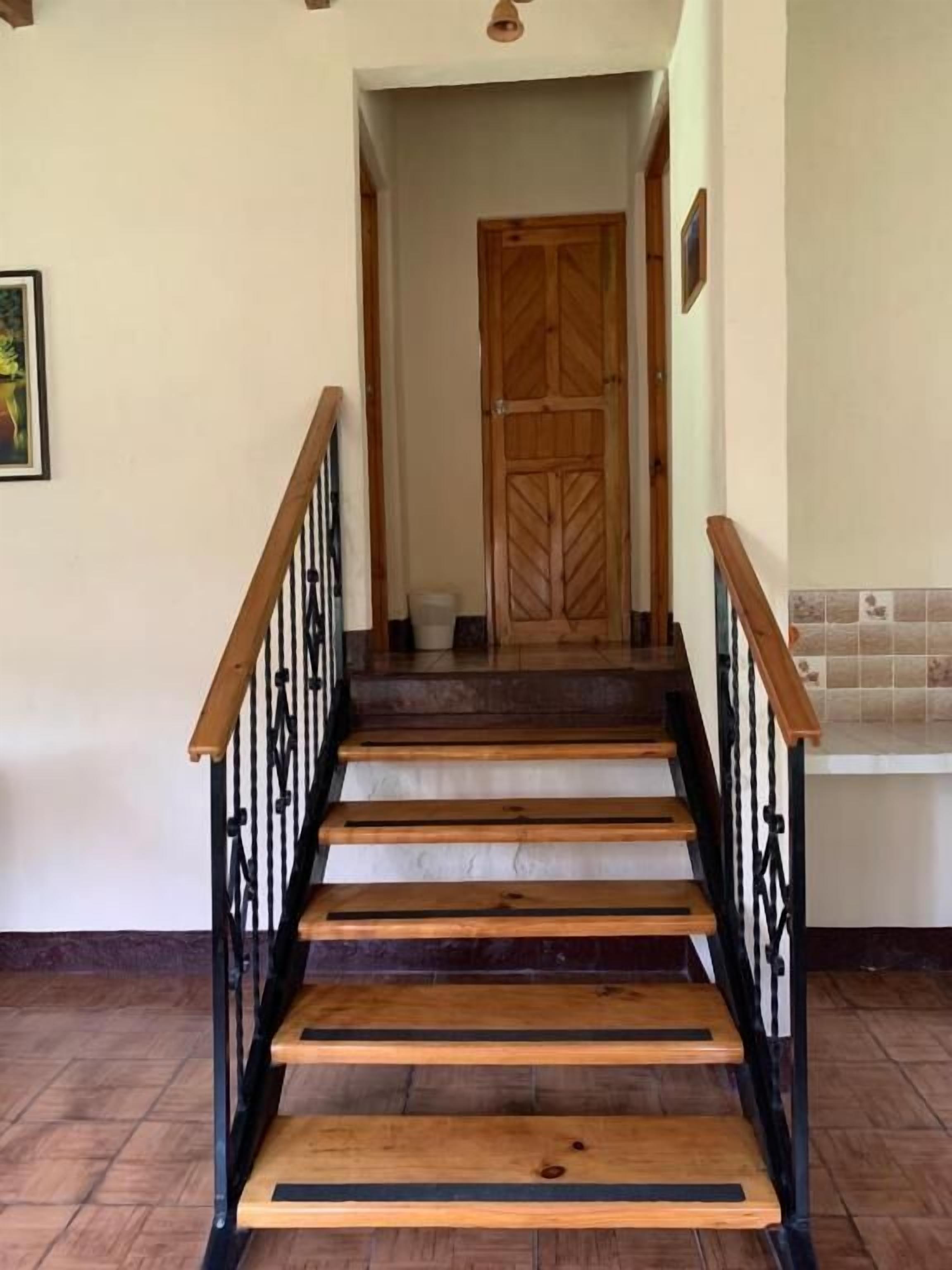 Uma escada de madeira com grades pretas que leva a uma porta.
