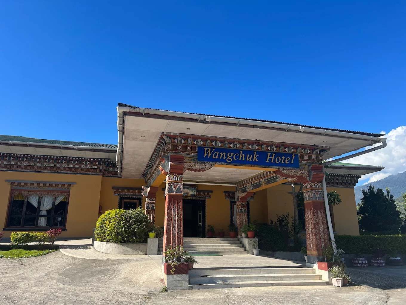 Um edifício com uma placa indicando 'Wangchuk Hotel' e uma entrada coberta com degraus.