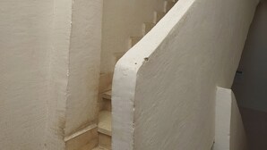 Uma escadaria com paredes brancas e uma porta marrom no topo.