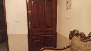 Um quarto com porta de madeira, interruptor de luz e cama com colcha estampada.