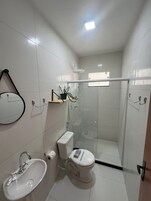 A bathroom with a toilet, sink, and shower area.