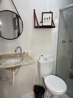 Uma casa de banho com uma pia, sanita e um quadro emoldurado na parede.