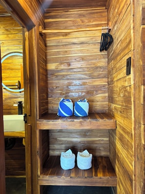 Uma sauna de madeira com duas toalhas em prateleiras e um porta-toalhas.
