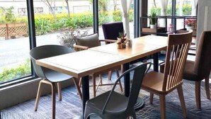 Uma sala de jantar com mesa e cadeiras, grandes janelas e vista para um edifício.