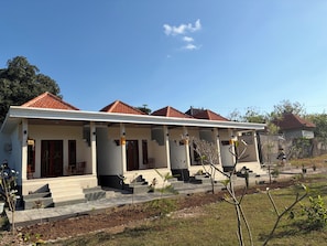 Uma casa de dois andares com varanda coberta, telhado de telhas e jardim ajardinado.