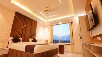 Quarto de hotel moderno com uma cama grande, televisão de tela plana, escrivaninha com telefone e janela com vista para a cidade.