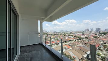 Uma varanda com vista para a cidade, corrimão de metal e chão de azulejos.