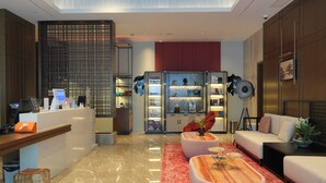 Um lobby moderno de hotel com uma receção, área de estar e um grande expositor.