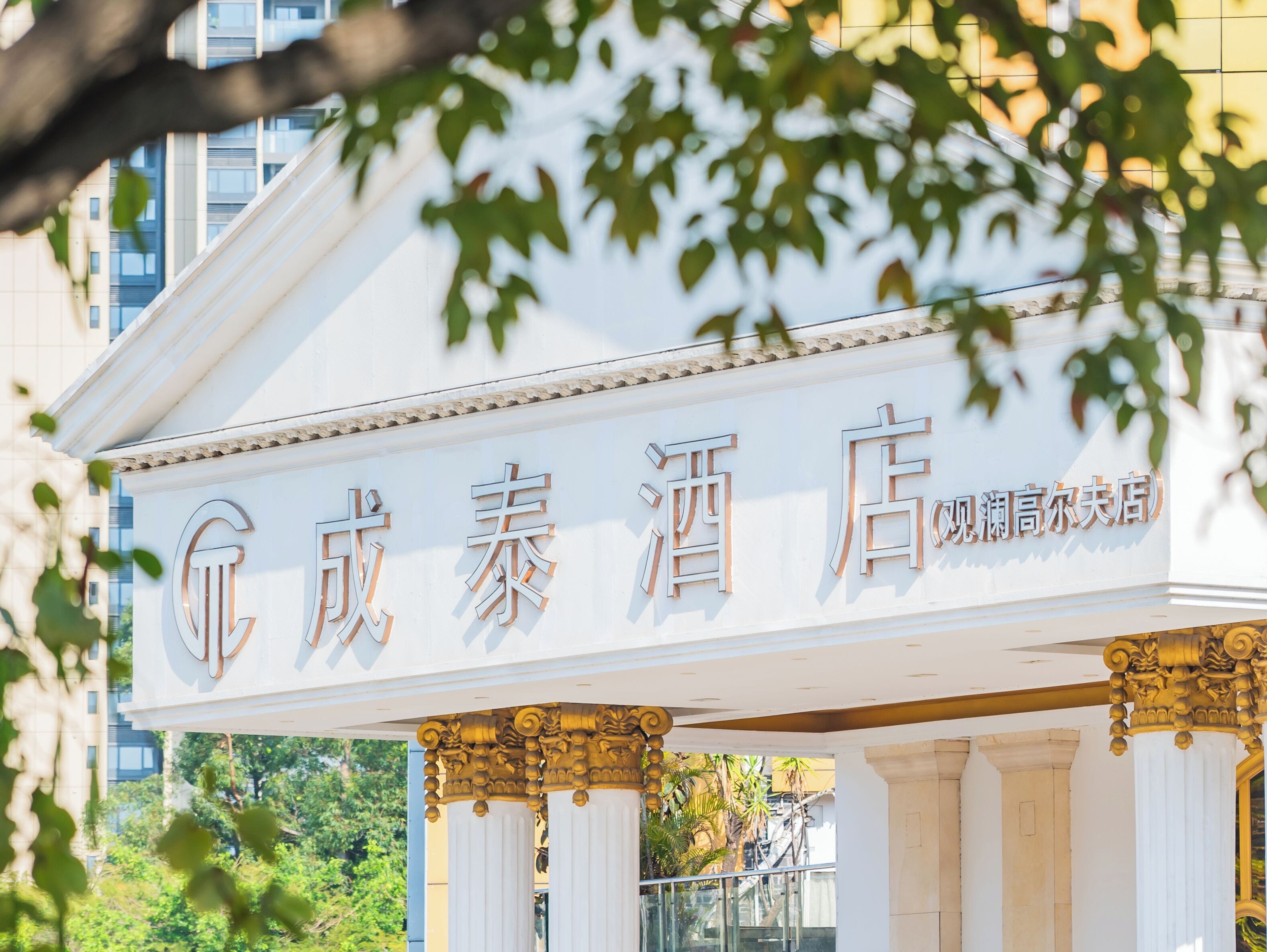 Placa de hotel com caracteres chineses e arquitetura clássica com colunas.