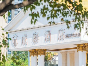 Placa de hotel com caracteres chineses e arquitetura clássica com colunas.