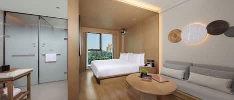 Quarto de hotel moderno com cama, sofá, mesa pequena e escrivaninha.