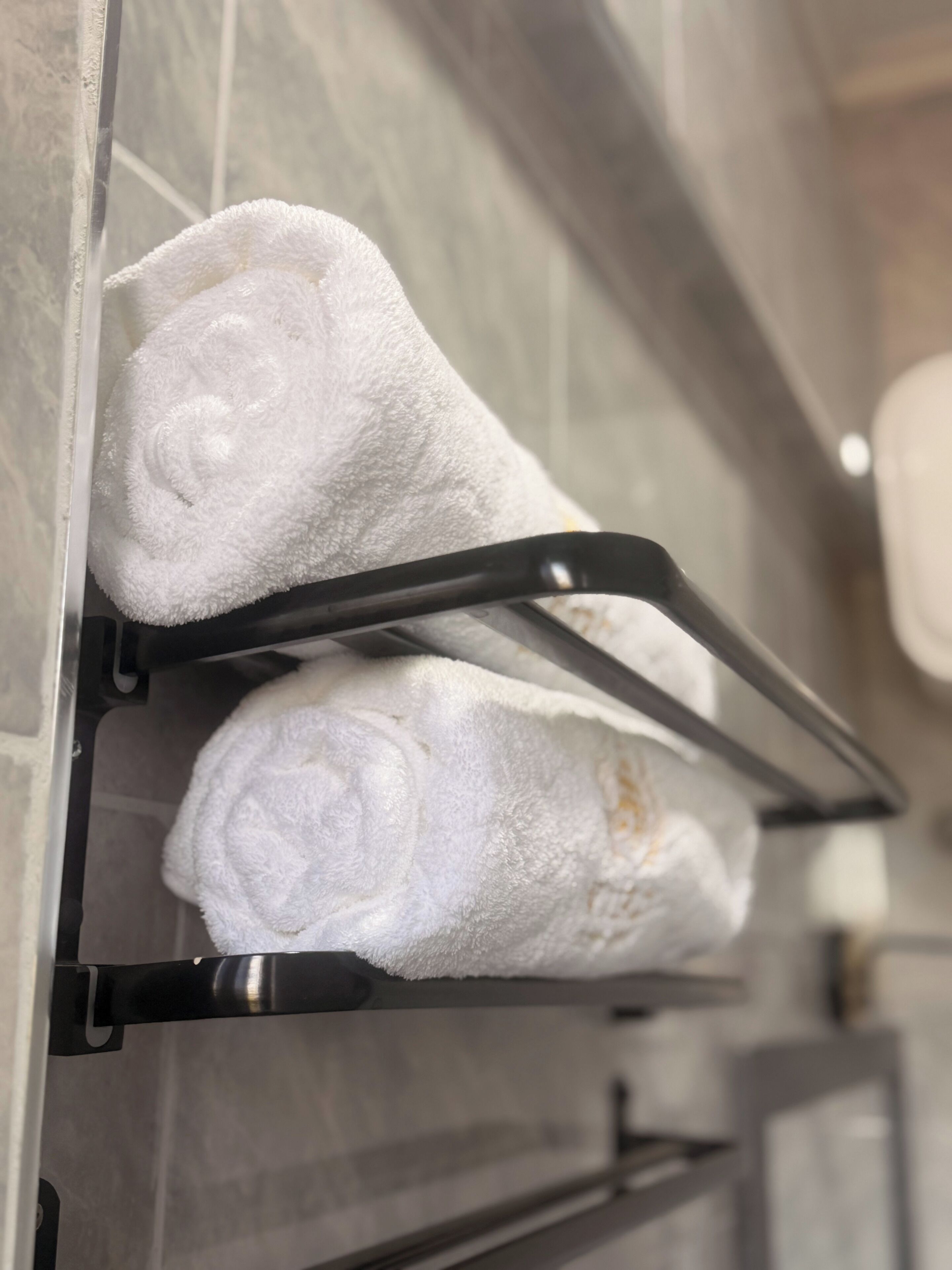 Casa de banho com porta-toalhas com duas toalhas enroladas.